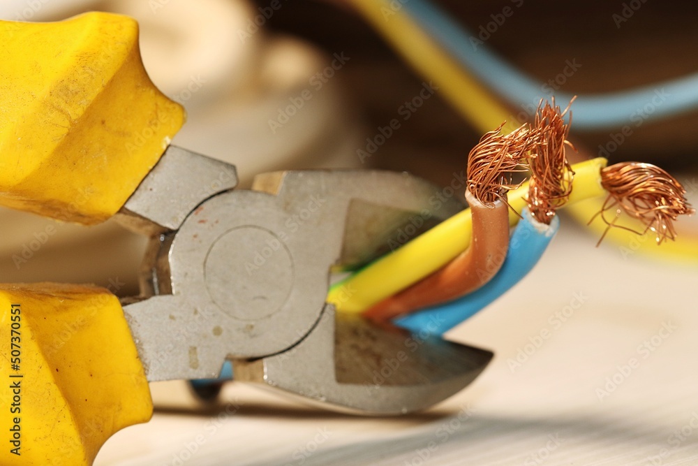 Electrical wires in the process of being cut with a side cutter. The ...