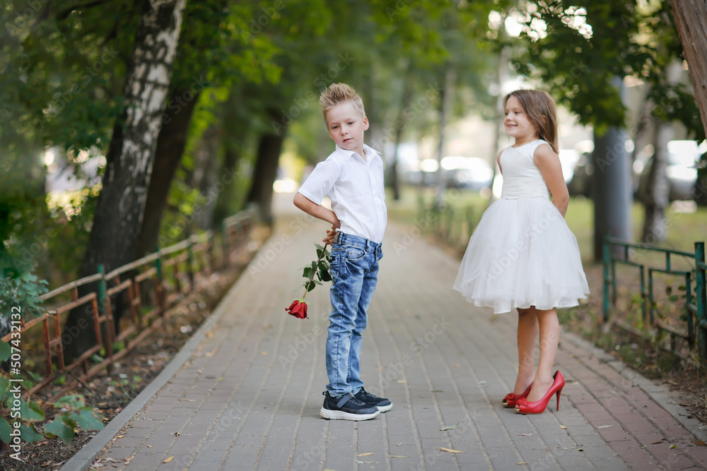 cute couple of children boy and girl, boy gives his girlfriend rose for ...