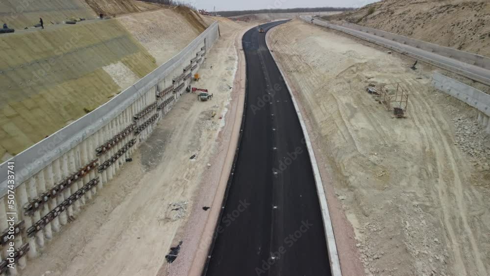 Workers reinforce the slope over the new road. Road construction in ...