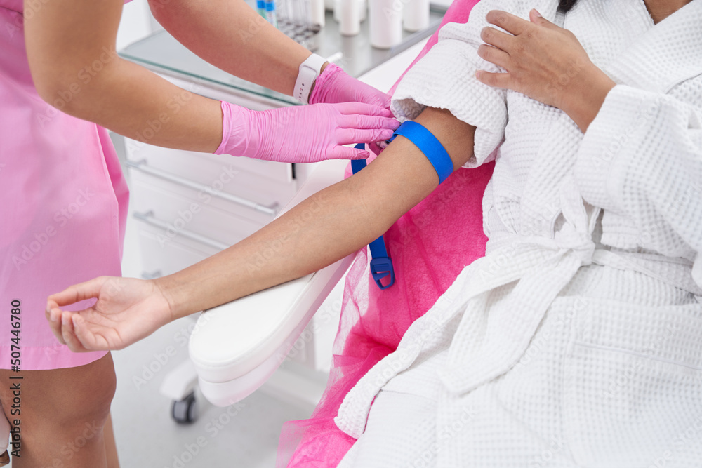 Medical worker puts clamp on arm of client before injection Stock Photo ...