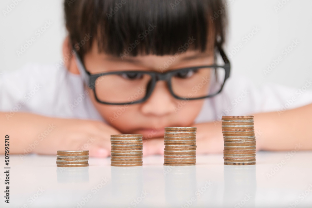 Cute asian little girl making stacks of coins. Little kids save money ...