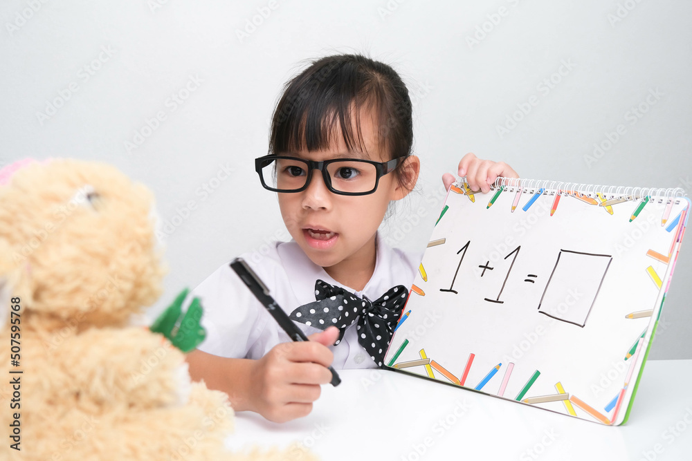 Cute Asian little girl playing teacher role game. A little girl is ...
