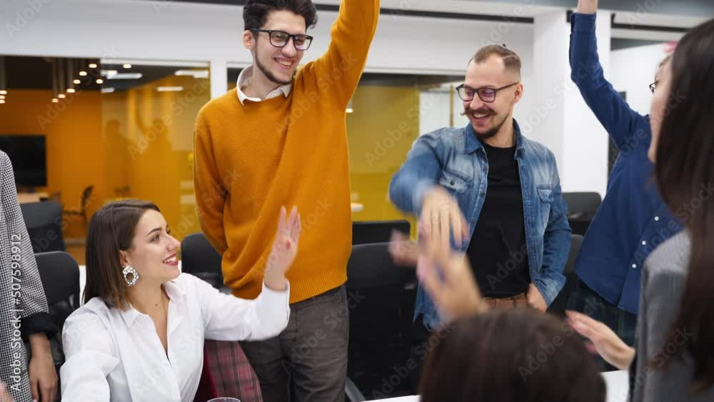 Business people stack hands in pile over meeting table, cheer together ...