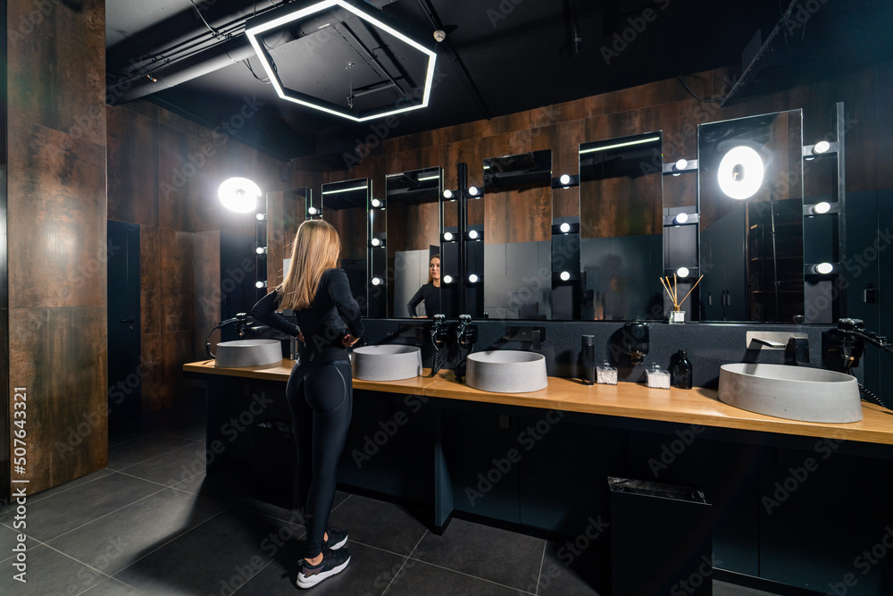 Gym club stylish interior with lady. Pretty woman in modern dark locker ...