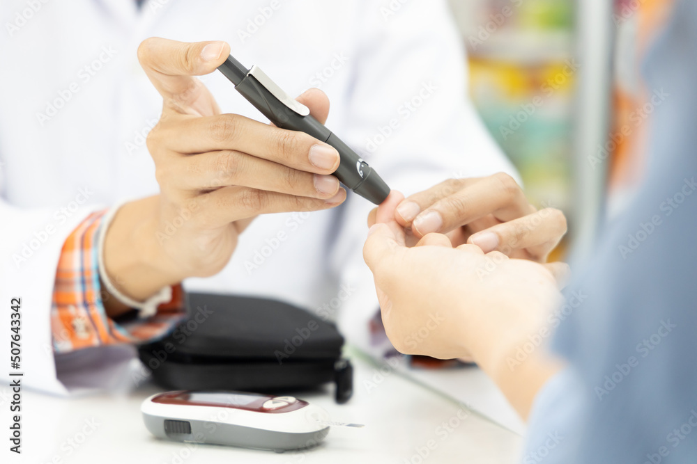 Asian woman pharmacist taking blood sample from asian girl finger for ...
