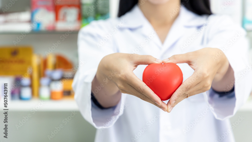 Asian female pharmacist doctor with red heart and pharmacy drug store ...