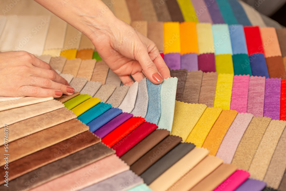 Fabric swatches in different colors are stacked for selection. A woman ...