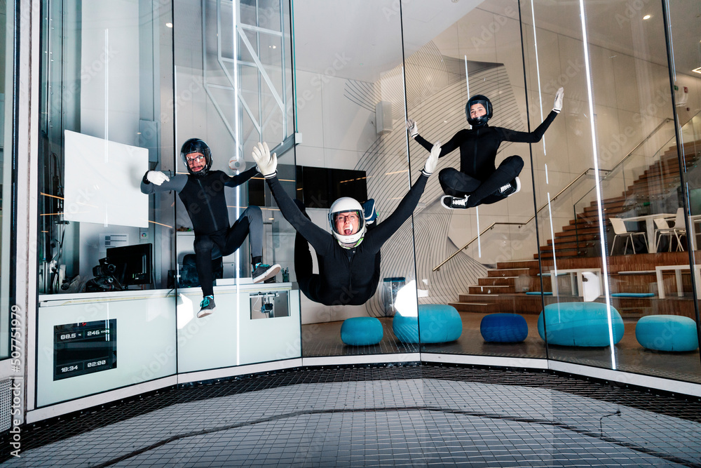 Happy man with friends flying in wind tunnel Stock Photo | Adobe Stock