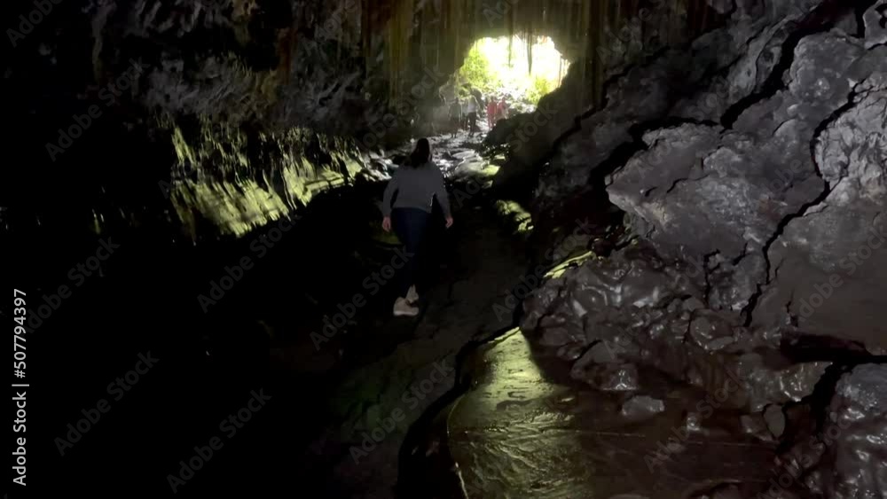 Lady walking and exploring the Kaumana Cave in Hawaii. Lava tube from ...