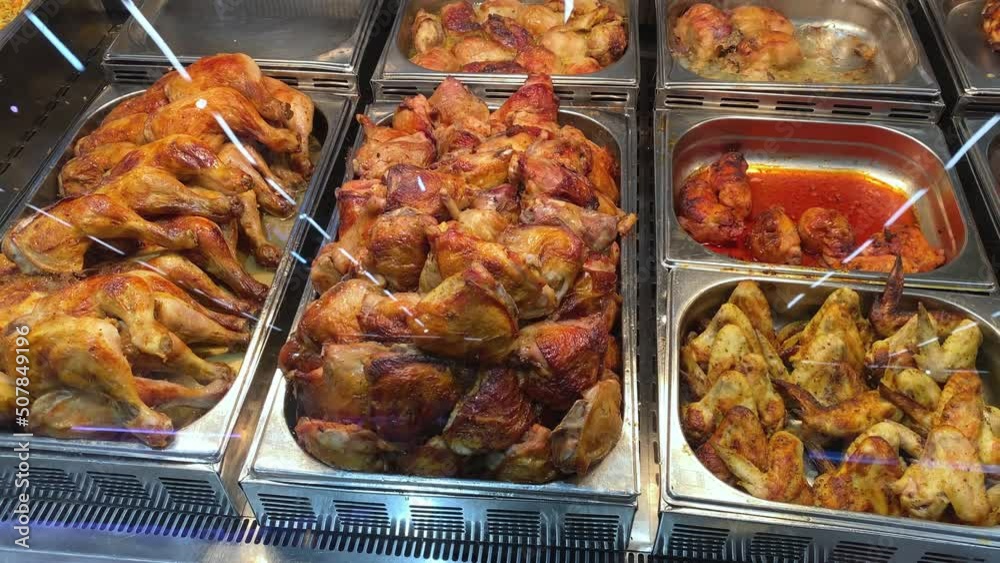 Supermarket display case with grilled chicken dishes. Fried legs ...
