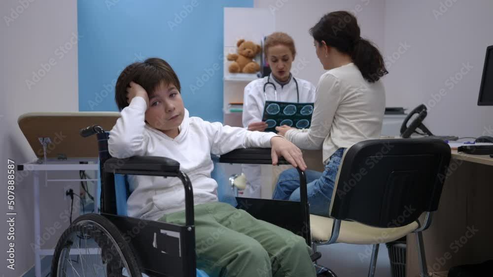 Bored tired Caucasian boy in wheelchair sighing looking at camera as ...