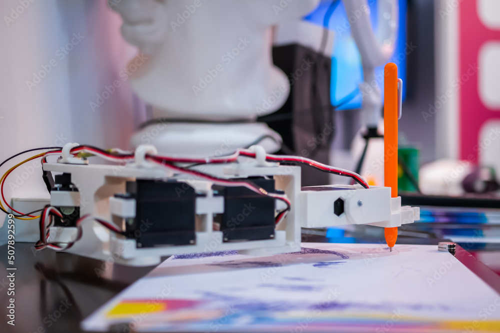 Programmed robotic white manipulator arm with orange pen drawing ...