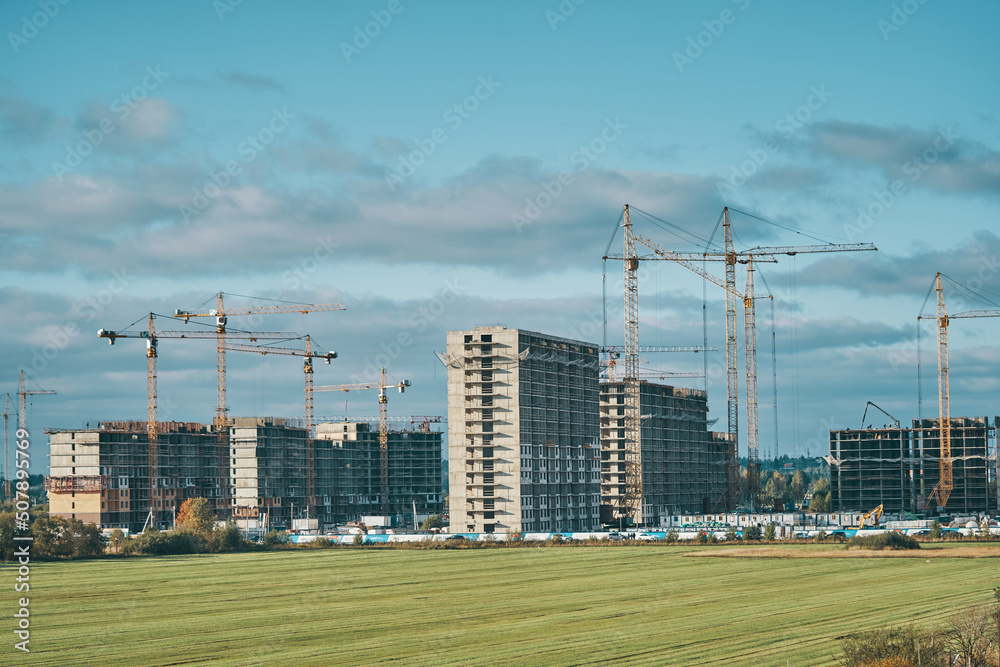 Building site with industrial construction cranes, multi-storey houses ...