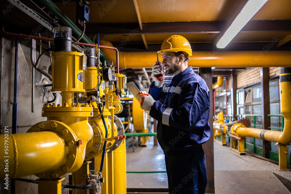 Professional caucasian refinery worker in safety equipment checking gas ...