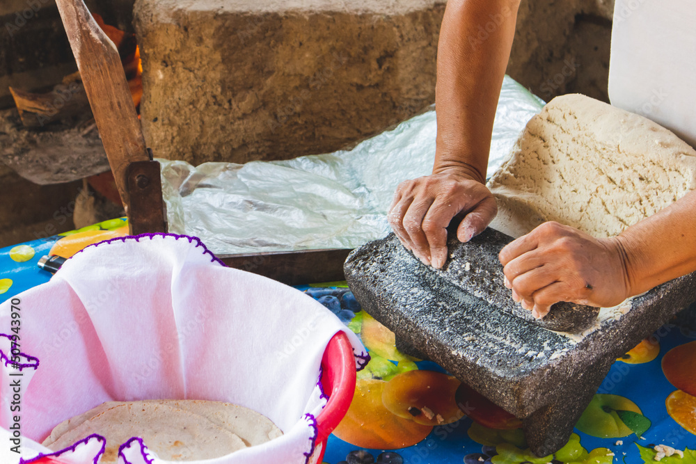 Foto de Mujer mexicana torteando maza de maíz en un metate y una estufa ...