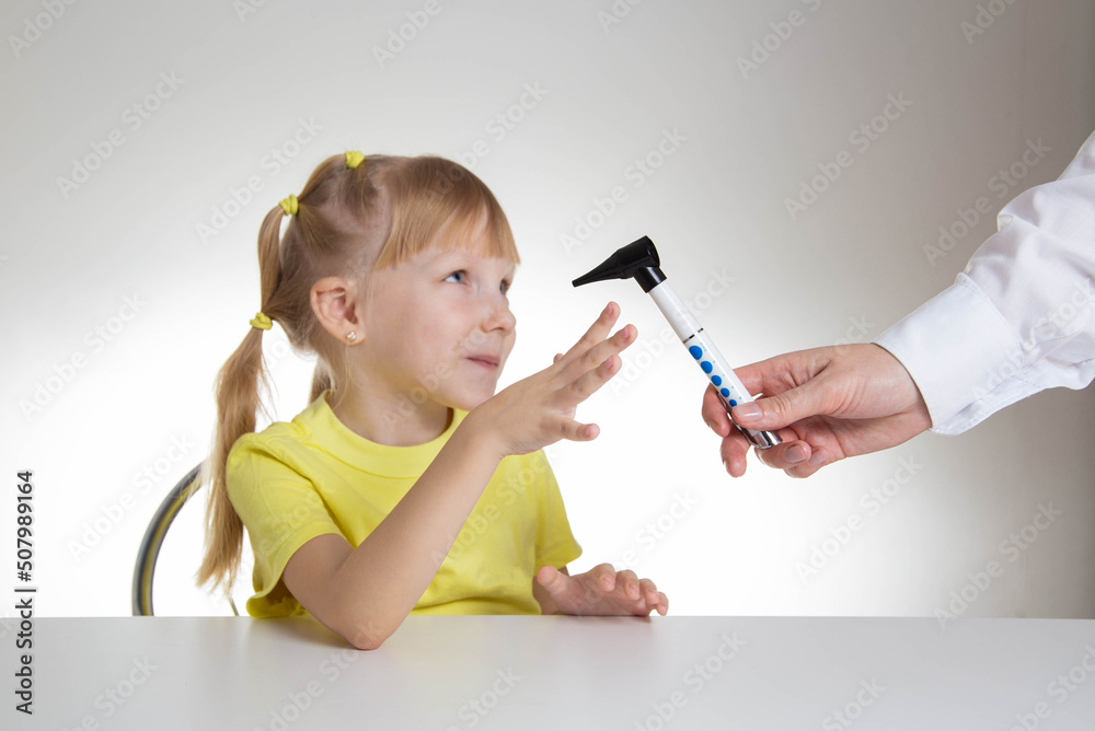 The doctor examines the ear canal of a little caucasian girl 5 years ...