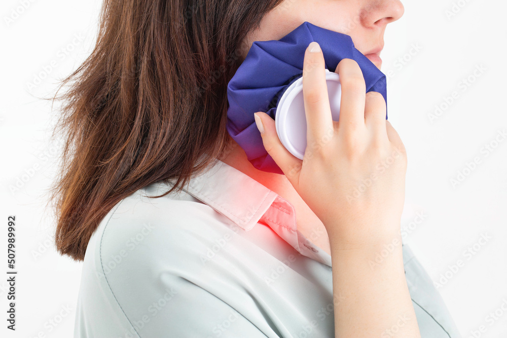 A girl attaches a medical bag with cold to the swelling on her cheek ...