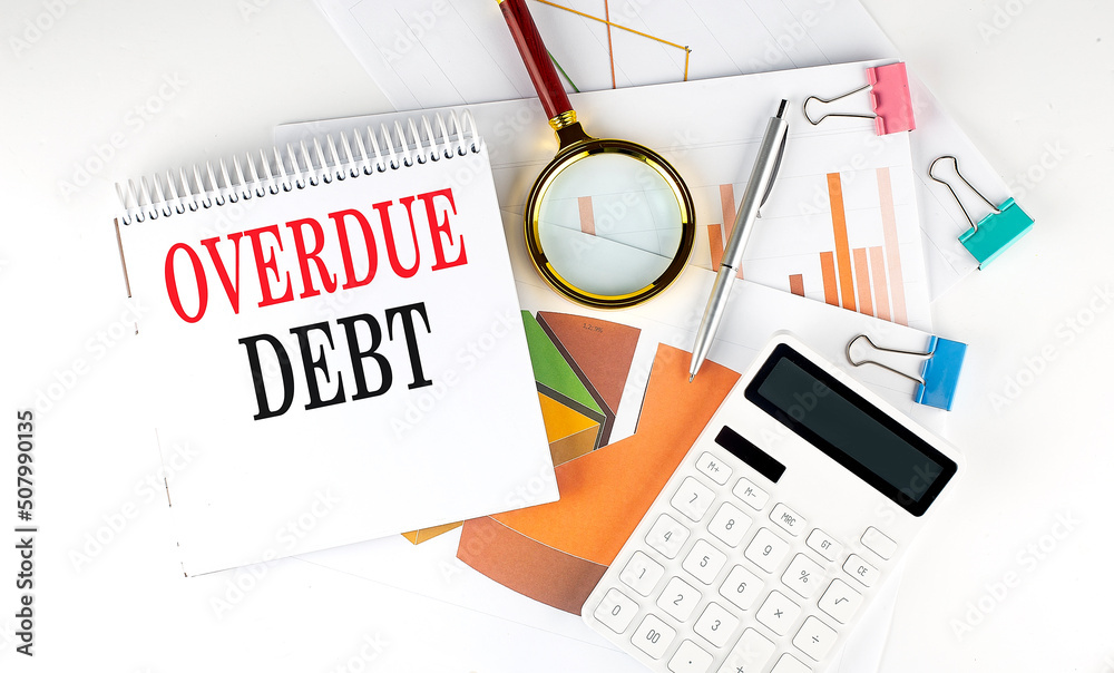 White notepad text OVERDUE DEBT with diagram,chart,calculator on the ...
