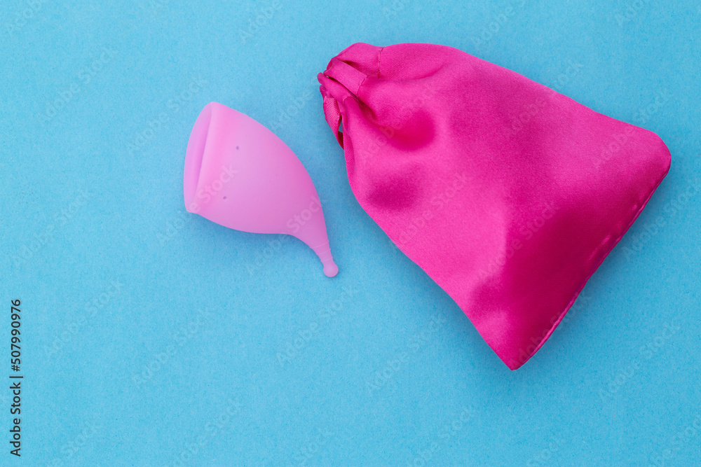 Pink menstrual cup and cover on a light blue background. Modern ...