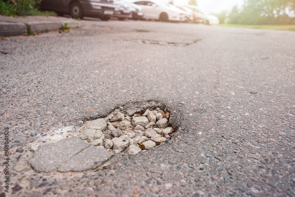 Pothole filled with pebbles on asphalt road in city. Problem of traffic ...