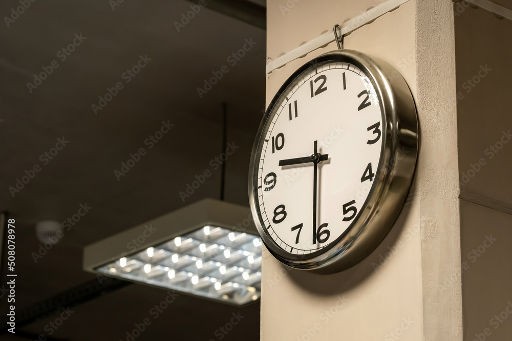 One single simple industrial clock in a factory hall or a corporate ...