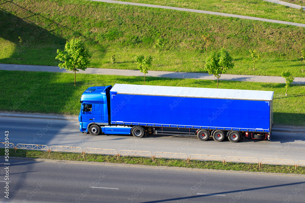 Blue semi truck lorry with trailer in motion on freeway. Big commercial ...