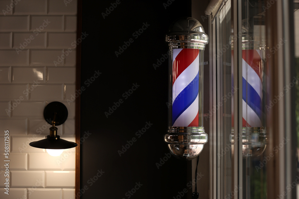 Barber pole spinning at night. International barbershop pole sign. A ...