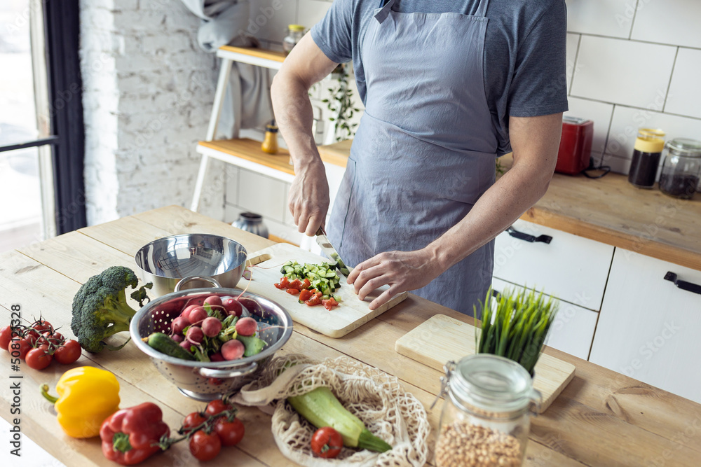 Handsome father, strong young man cooking healthy vegetable salad with ...