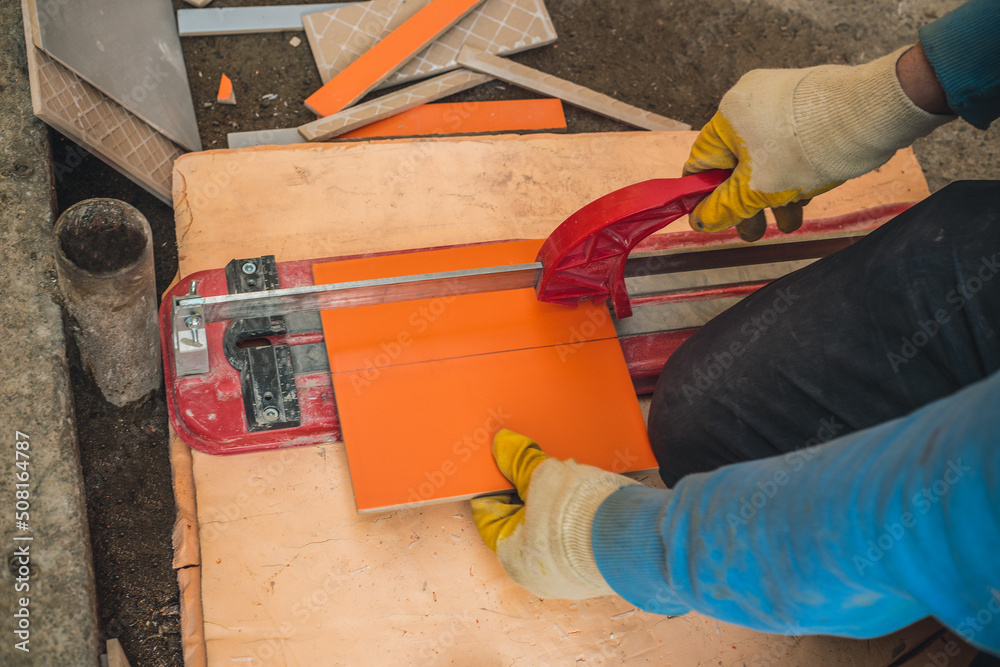 Manual tile cutter. A worker cuts a tile with a tile cutter top view ...