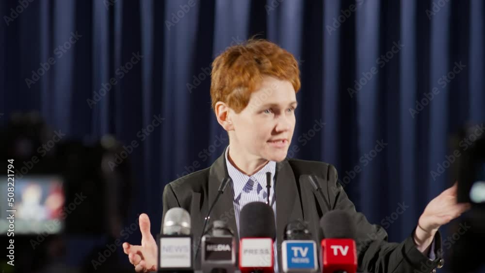 Female politician standing at rostrum with lots of microphones and ...