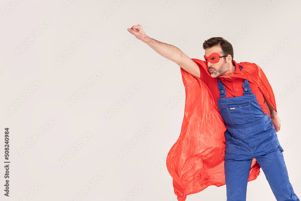 Handsome handyman in red cape and mask as a super hero posing isolated ...