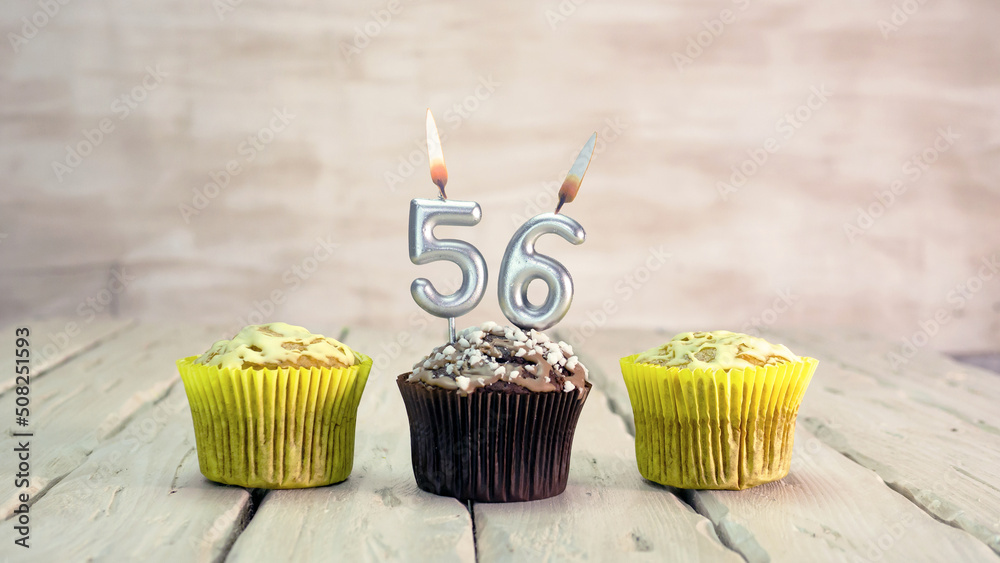 Happy birthday muffins with candles with the number 56. Card copy space ...