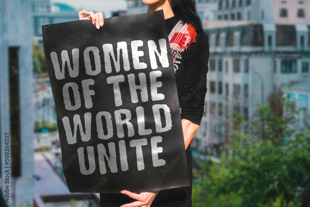The phrase " Women of the world unite " is on a banner in women's hand ...
