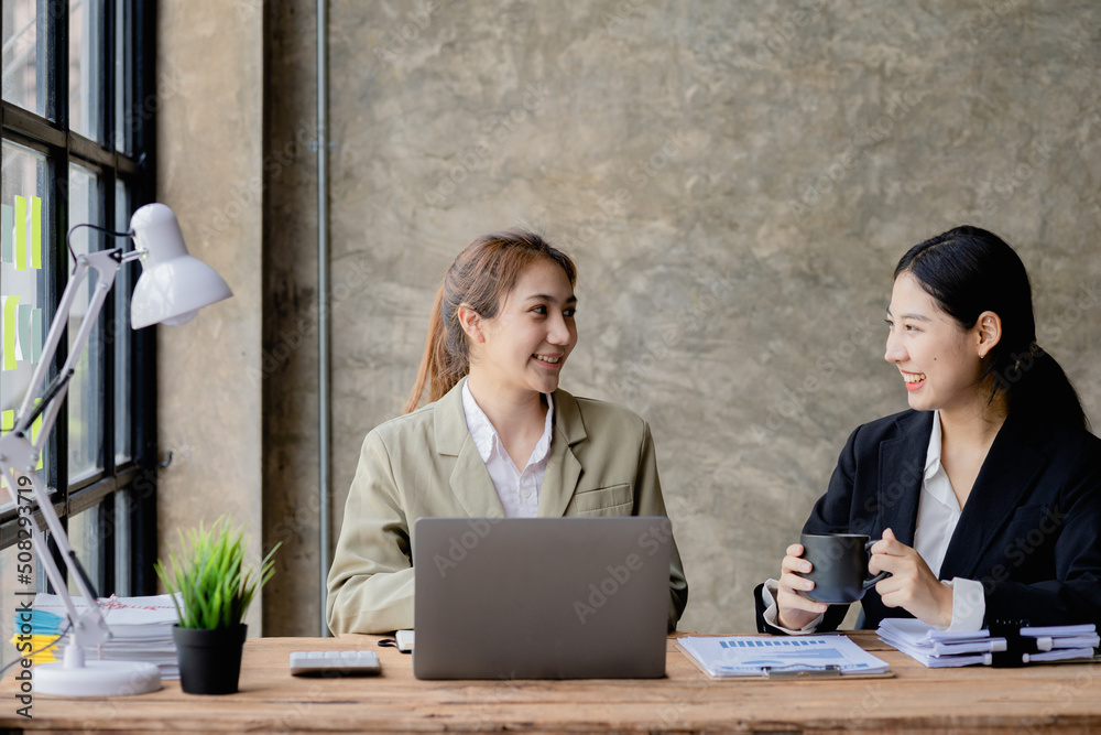 Two Asian business women are meeting to summarize the company's operating, financial, profit and ...