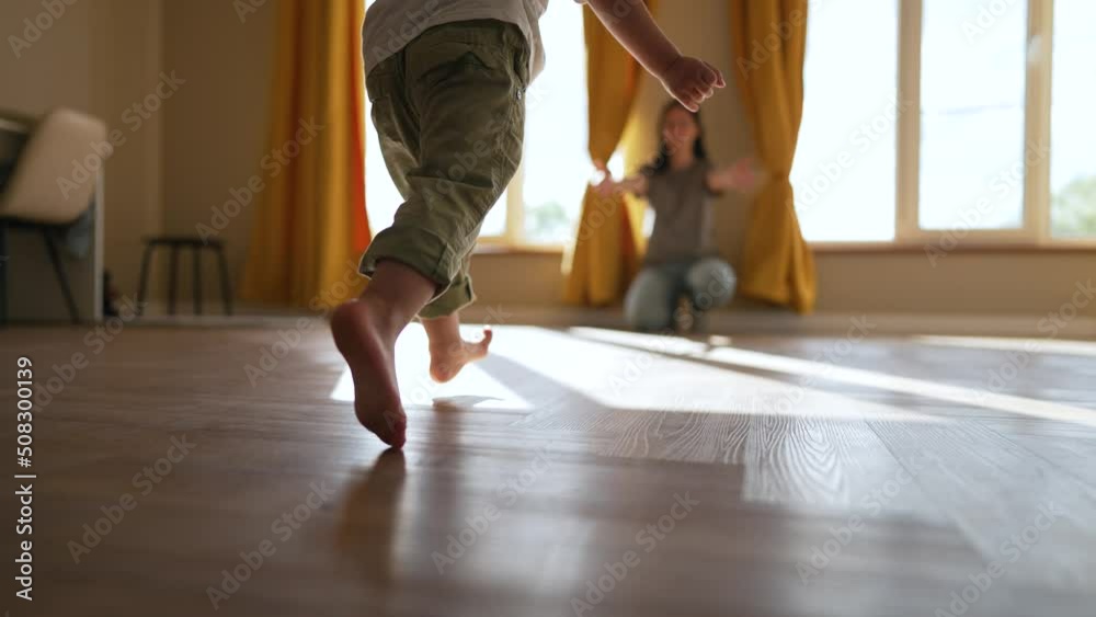 Happy family. Baby feet walk on floor towards mother. Child makes steps ...
