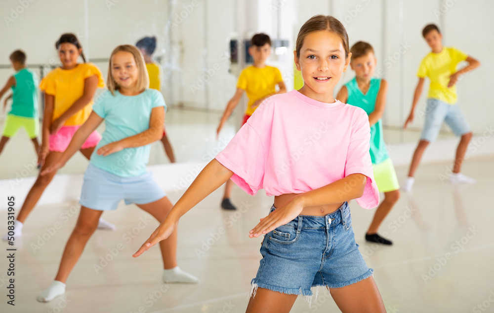 Happy tween girl dancing with children during group class in modern ...