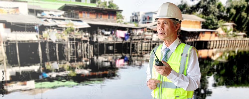 Middle-aged civil engineer wearing hard hat on waterfront slum ...
