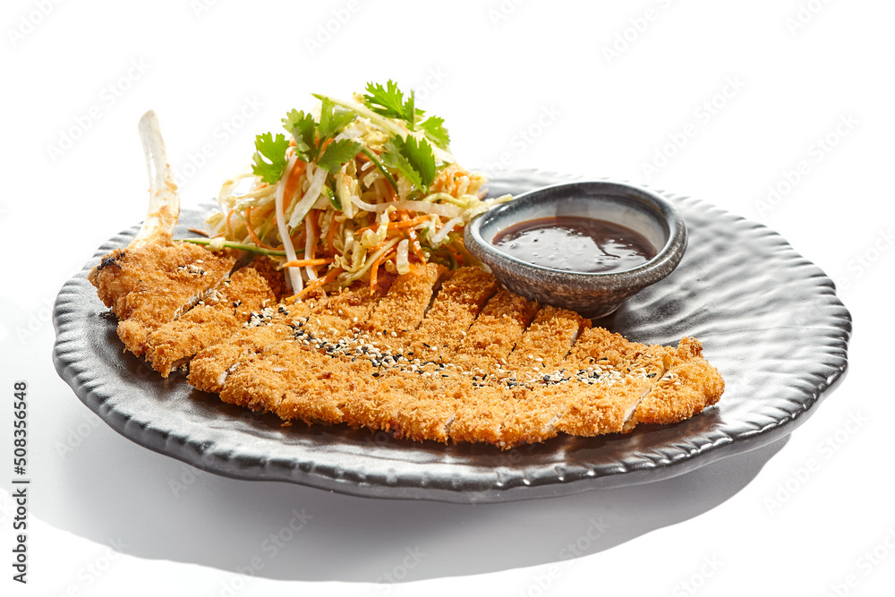 Authentic German schnitzel with cabbage salat and sauce on black plate ...