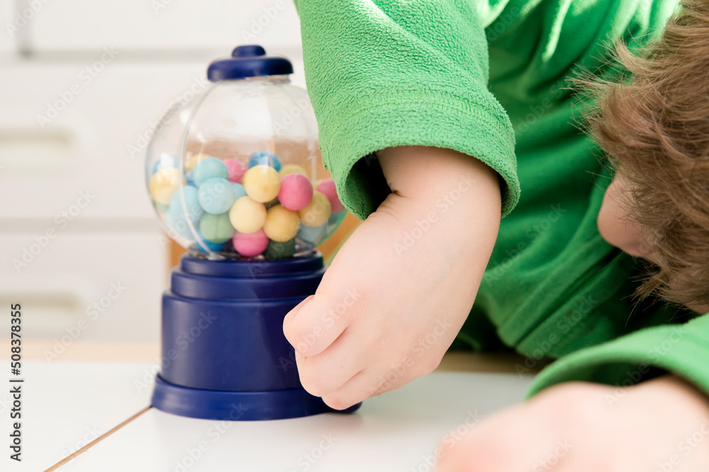 Beautiful boy plays with candy machine. Gumball Machine toy with ...