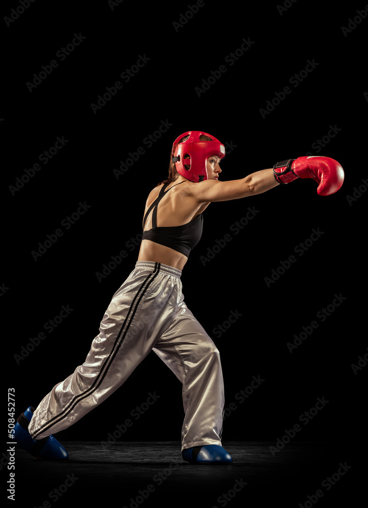 Young female boxer in boxing gloves and helmet training isolated on ...