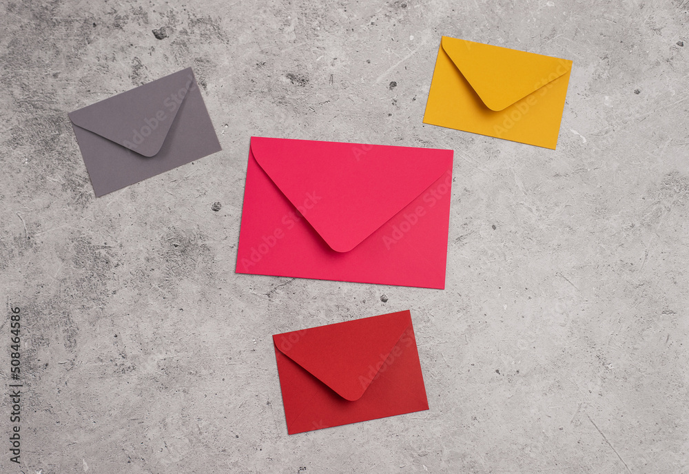 Four envelopes of a different color on a light concrete background ...