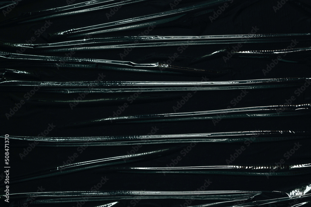 Black plastic wrap background. Crumpled wrinkled plastic cellophane ...