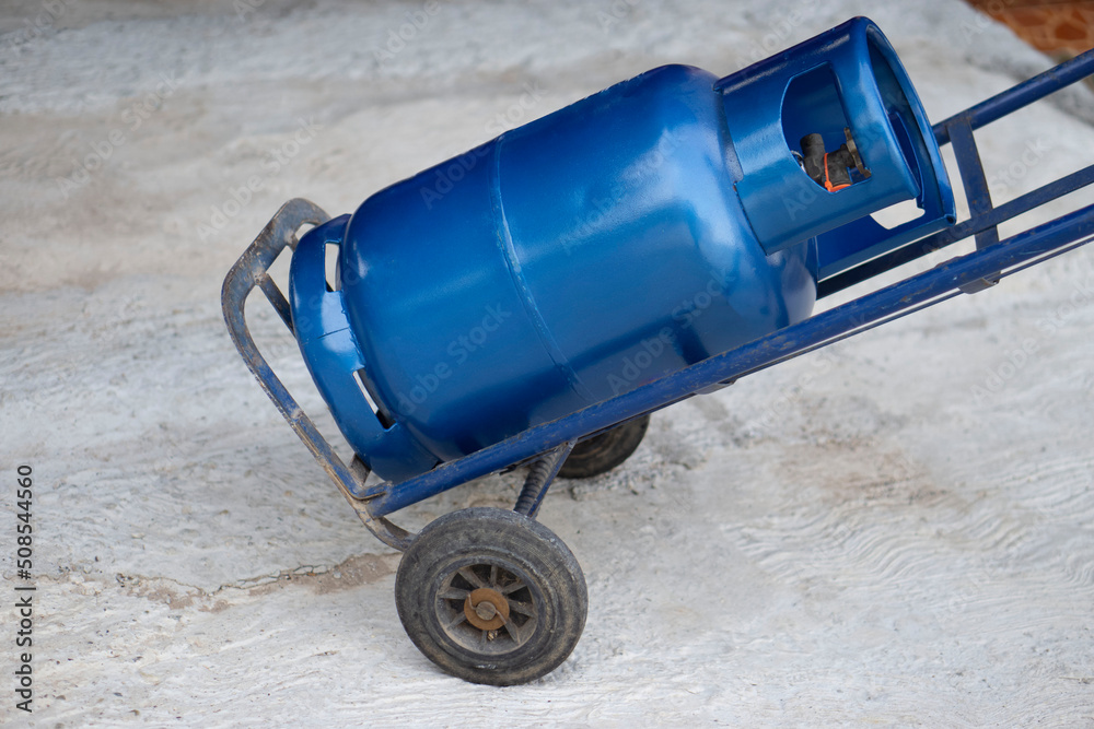Blue LPG gas cylinder tank on small cart to make delivery to local ...