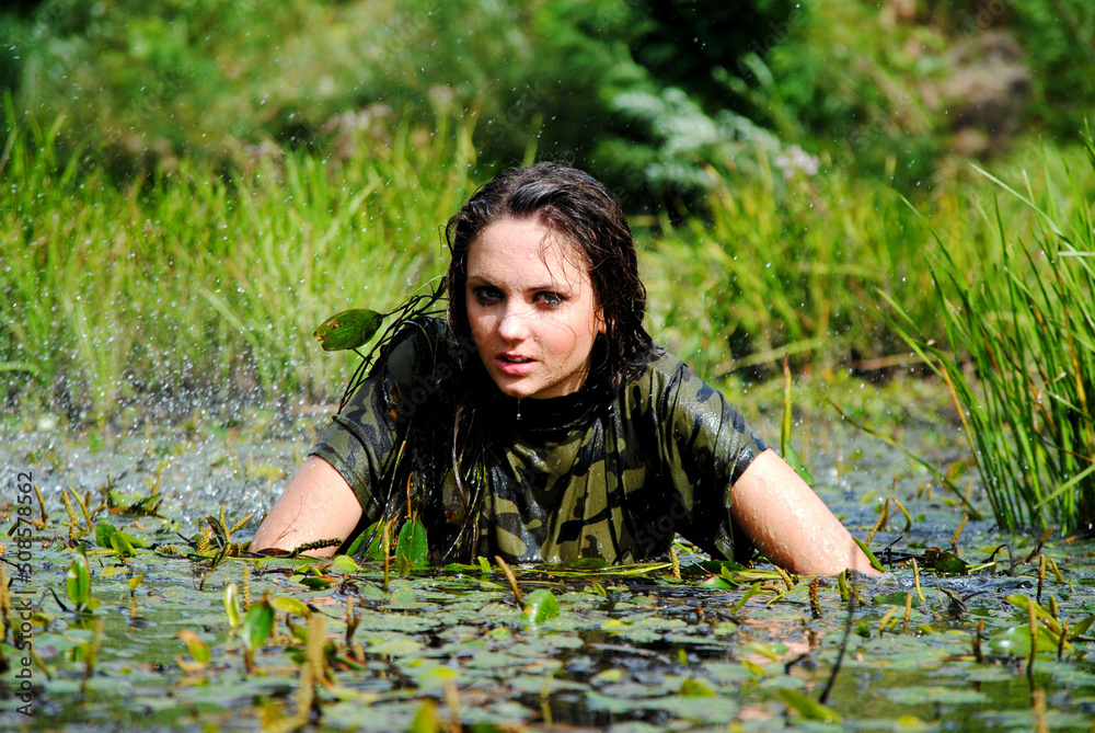 wet beautiful young girl in military uniform in the Ukrainian swamp, a ...