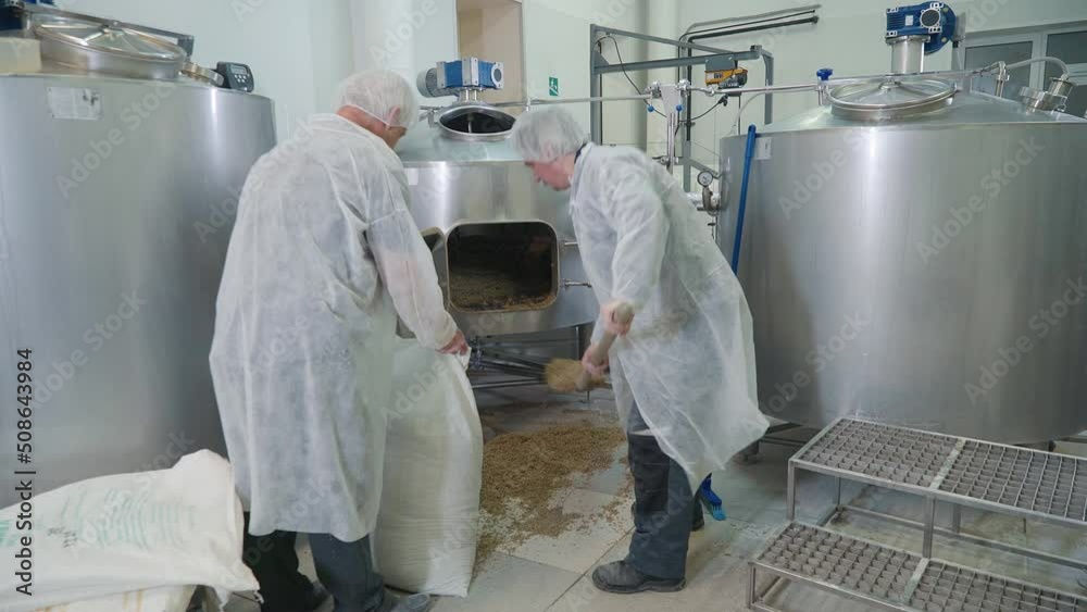Workers are collecting the grain waste after the beer production ...