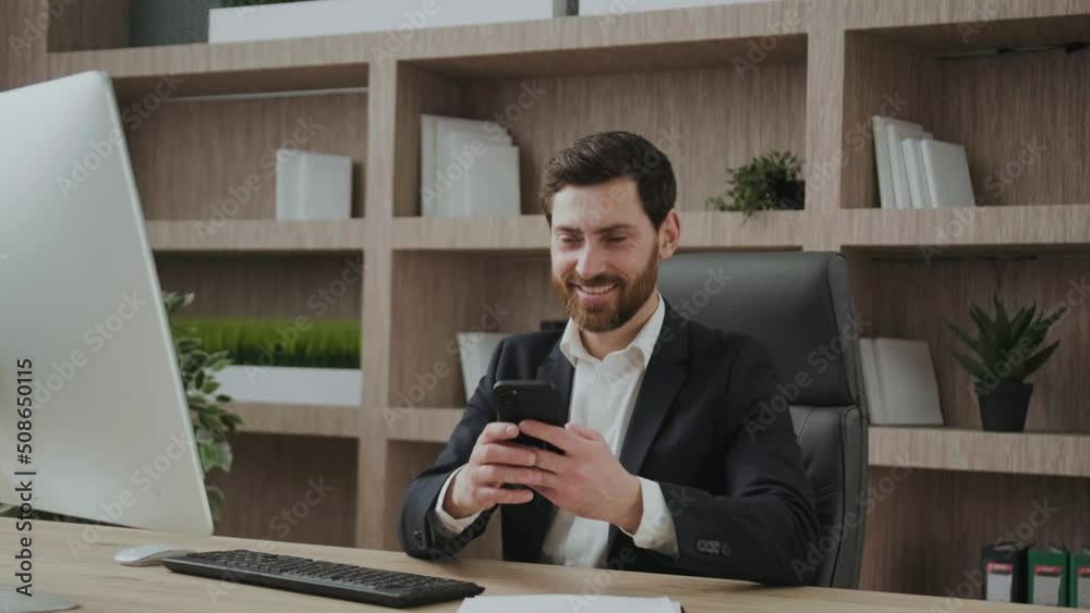 Smiling employee charts on a phone at his workplace. Looking into the ...