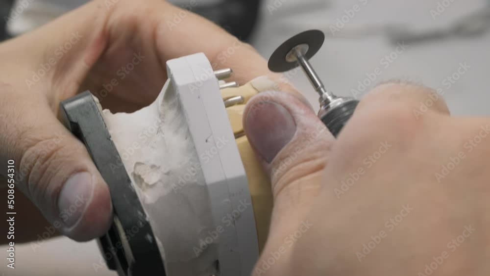 Worker is polishing the model of the dental substitution. Polishing the ...