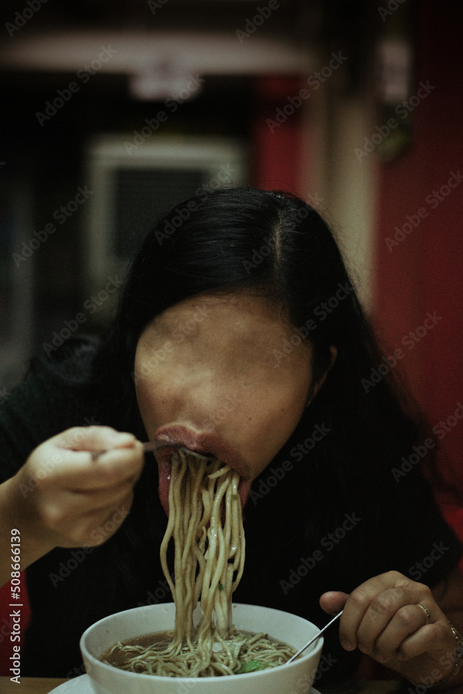 Surreal woman with big mouth eating noodles. Stock Photo | Adobe Stock