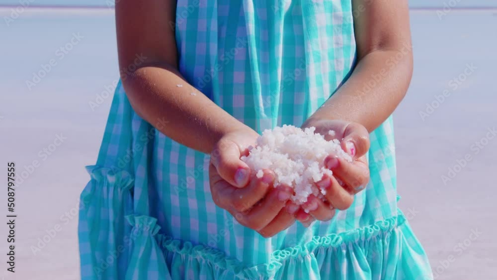 Faceless little girl holding handful of salt crystals in front of her ...