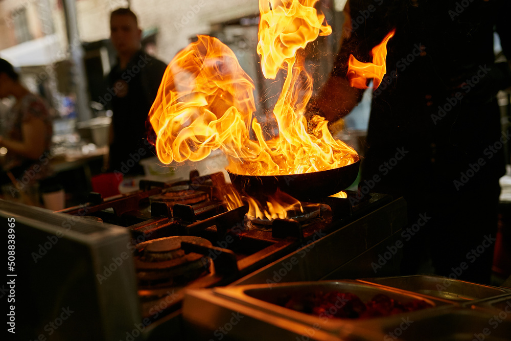 flame in the pan. Professional Chef makes flambe for food in the ...